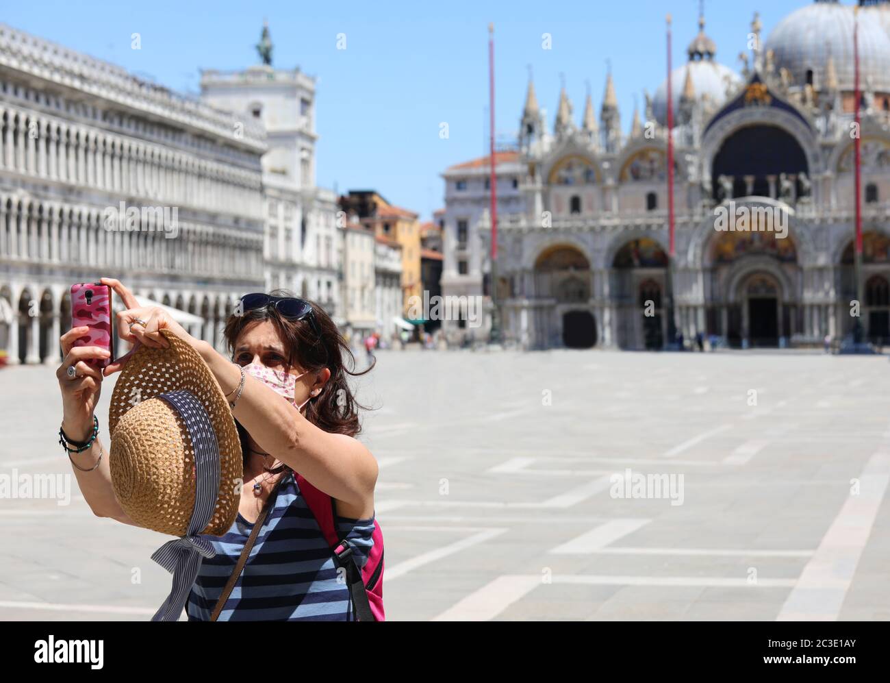 tourist wearing a surgical mask takes a picture in Venice during the ...
