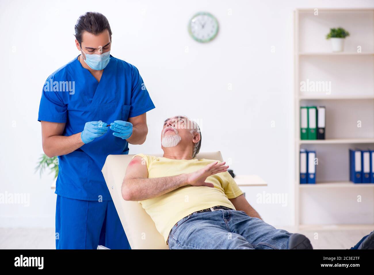 Injured old man visiting young male doctor traumatologist Stock Photo ...