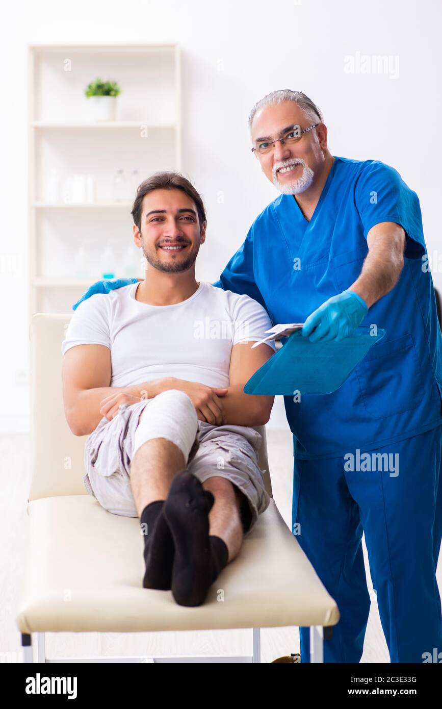 Leg injured man visiting old doctor in first aid concept Stock Photo ...