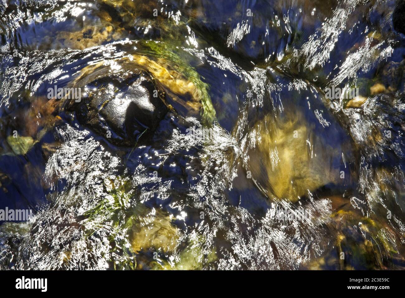 Detail view of flowing water, sun reflexes showing the direction of the ...