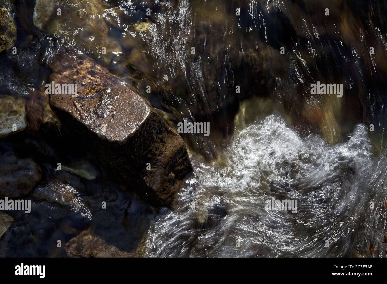 Detail view of flowing water, sun reflexes showing the direction of the ...