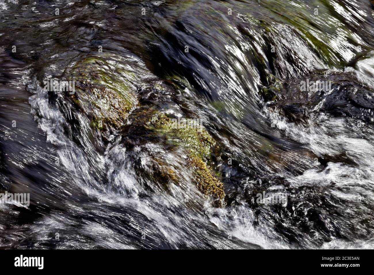 Detail view of flowing water, sun reflexes showing the direction of the ...