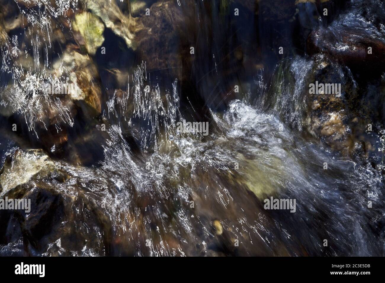 Detail view of flowing water, sun reflexes showing the direction of the ...