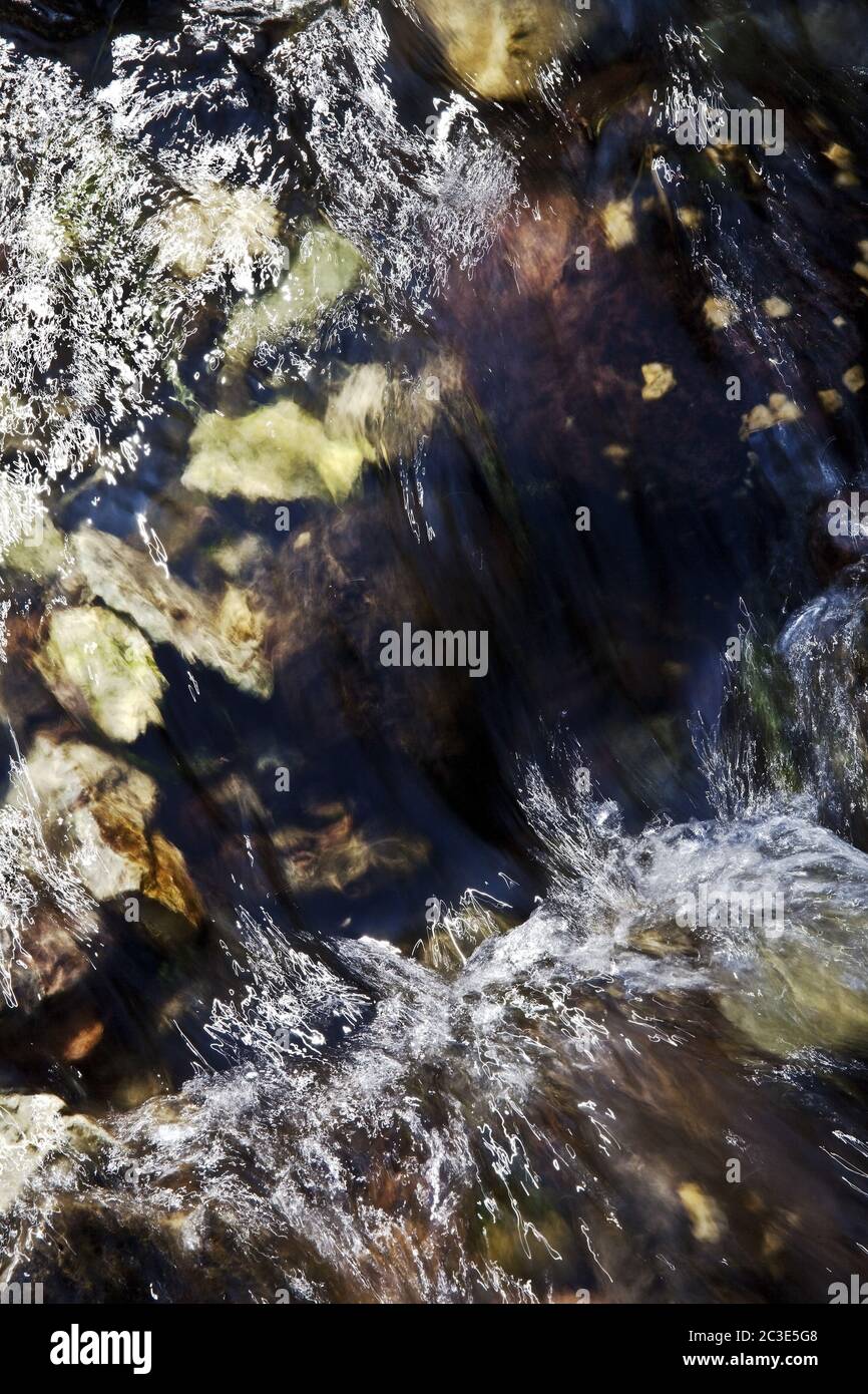 Detail view of flowing water, sun reflexes showing the direction of the ...