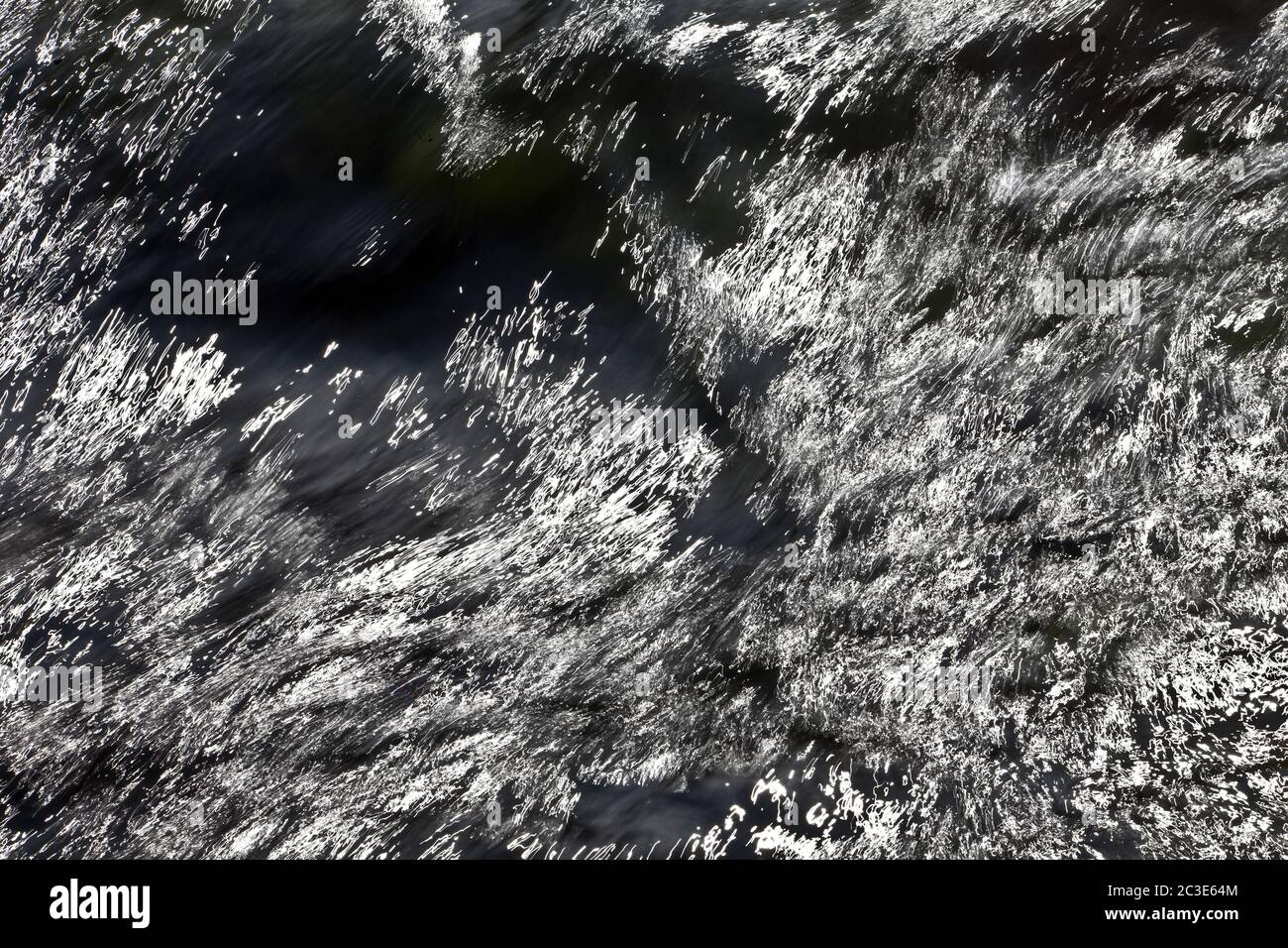 Detail view of flowing water, sun reflexes showing the direction of the ...