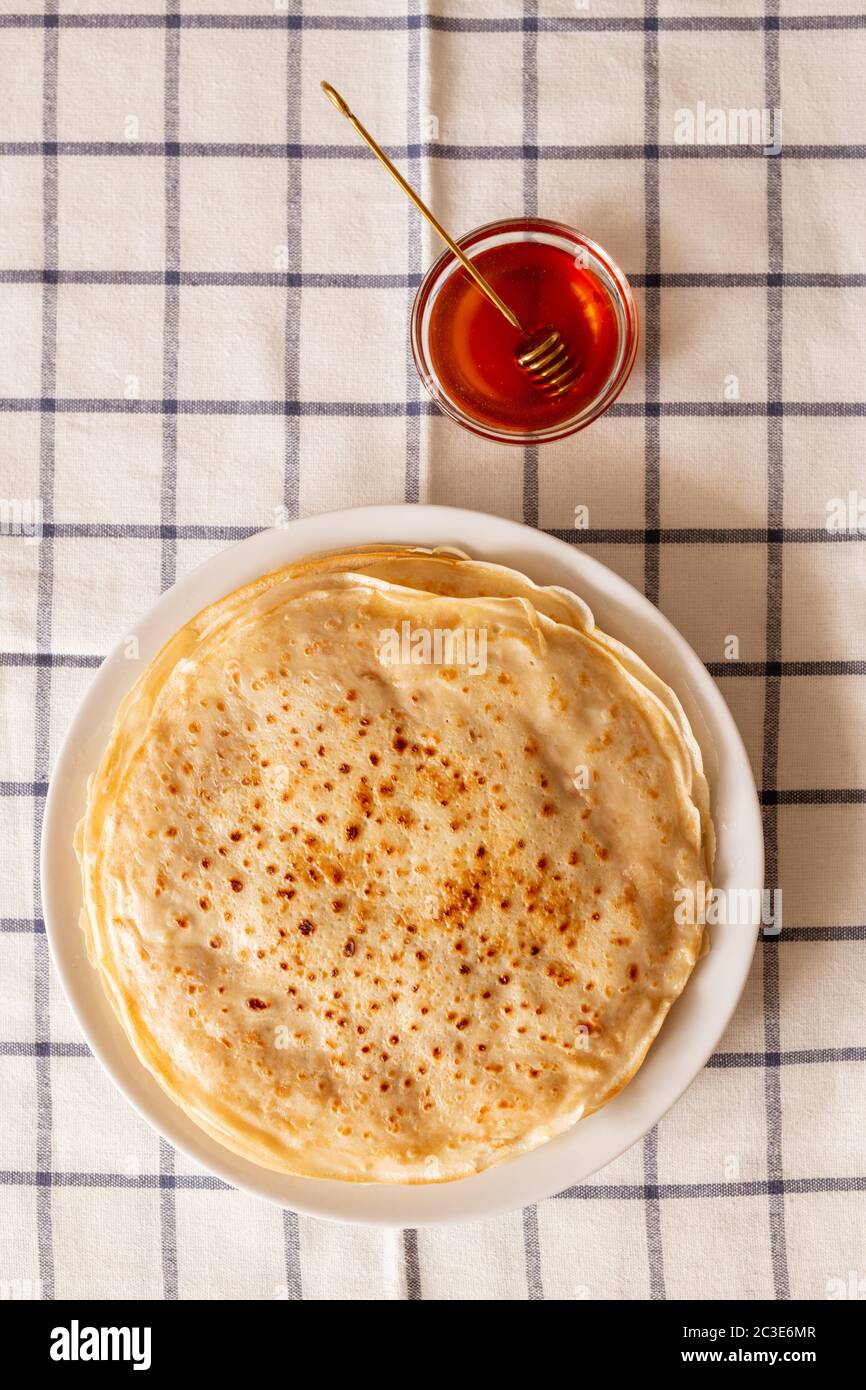 Top view of stack of fresh pancakes on plate with small bowl of flower ...