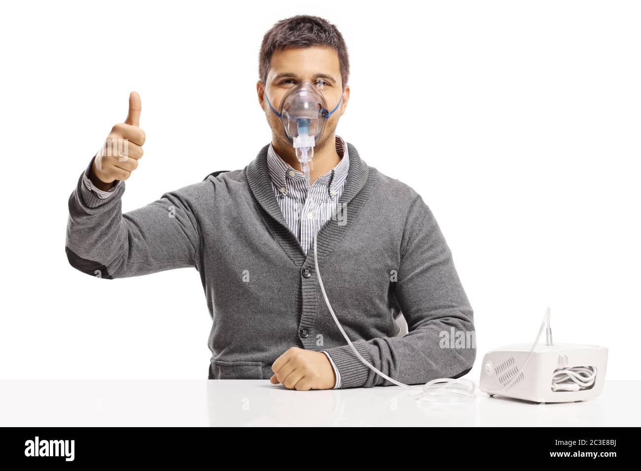 Young man using a nebulizer and showing thumbs up isolated on white ...