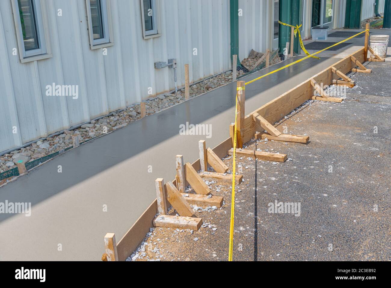 Horizontal shot of a freshly poured concrete sidewalk with caution tape ...