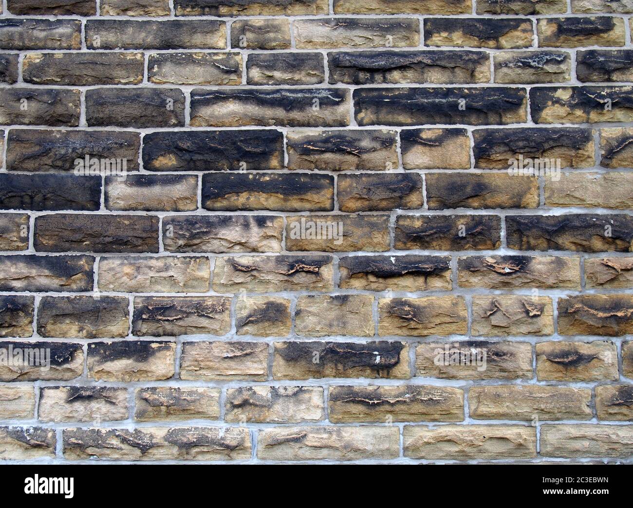 a full frame image of a large old dark stone wall made of large ...