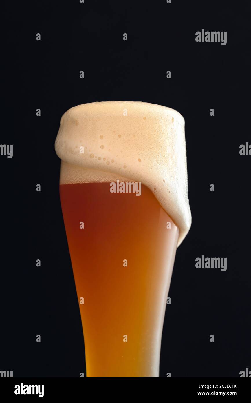 Cold white beer in a long classic glass with foam. German traditional ...