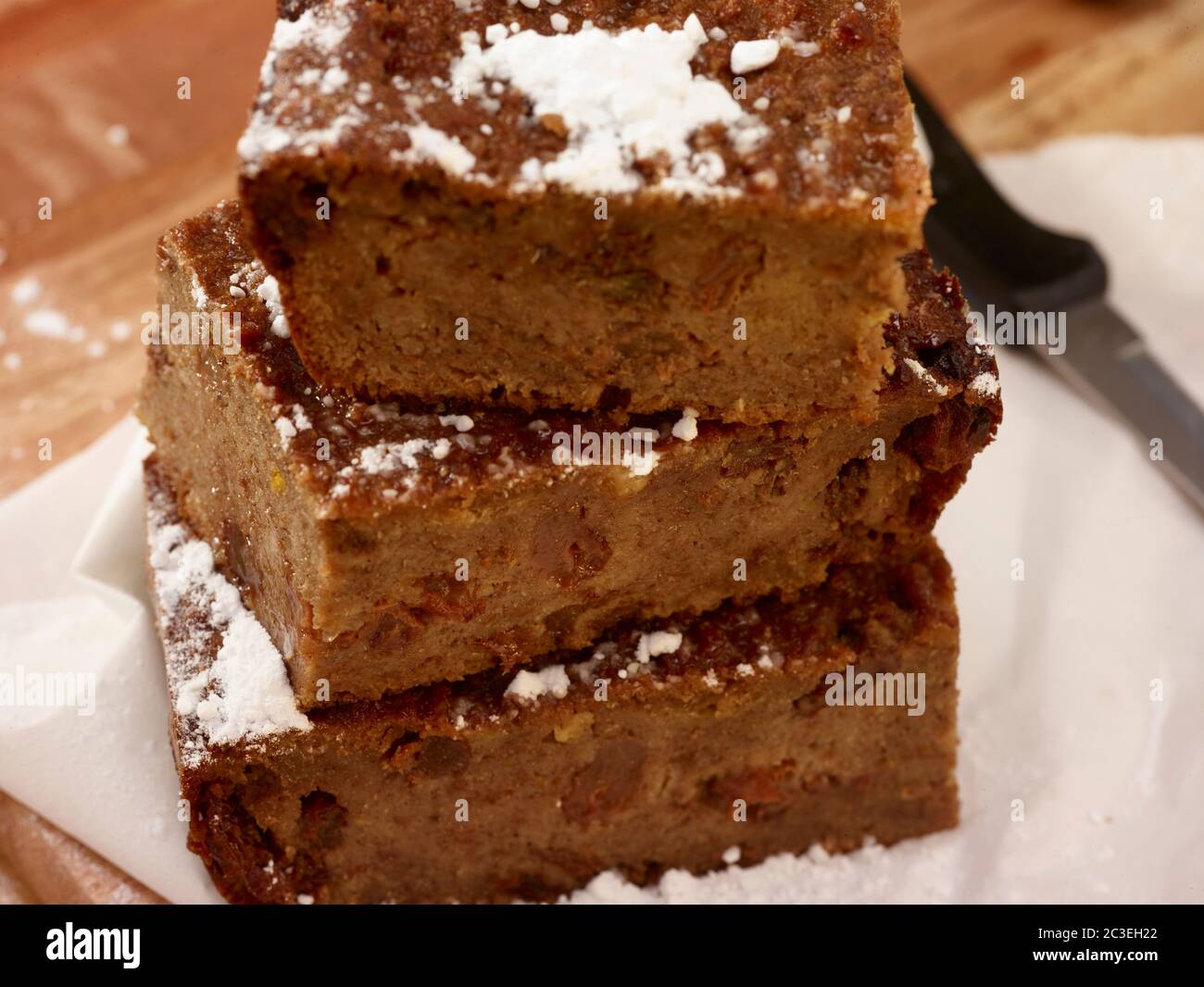Sliced Bread Pudding and icing sugar on greaseproof paper as if waiting ...