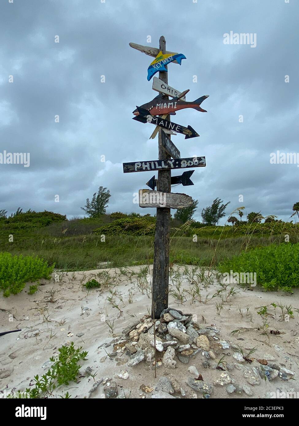 A city directional sign at a beach showing how far cities are from this ...