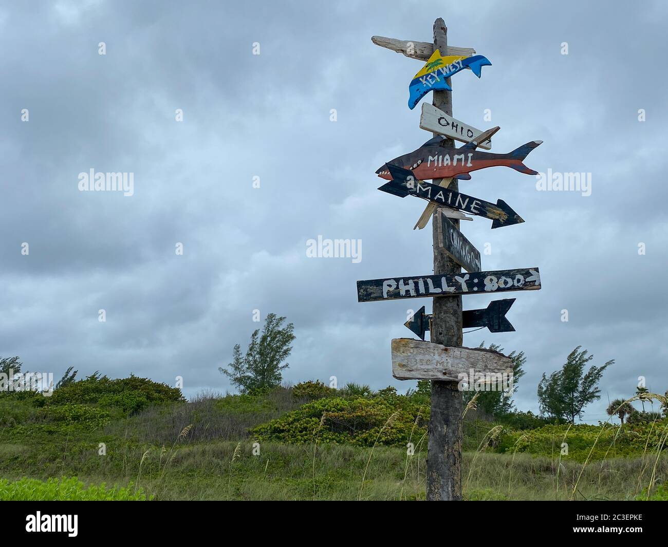 A city directional sign at a beach showing how far cities are from this ...