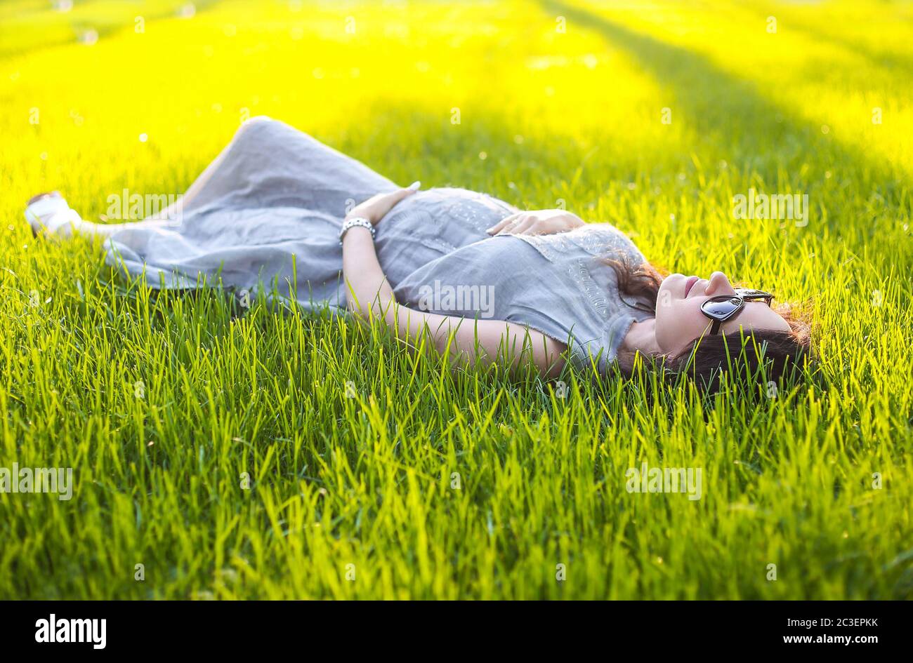Pregnant woman resting on lawn Stock Photo - Alamy