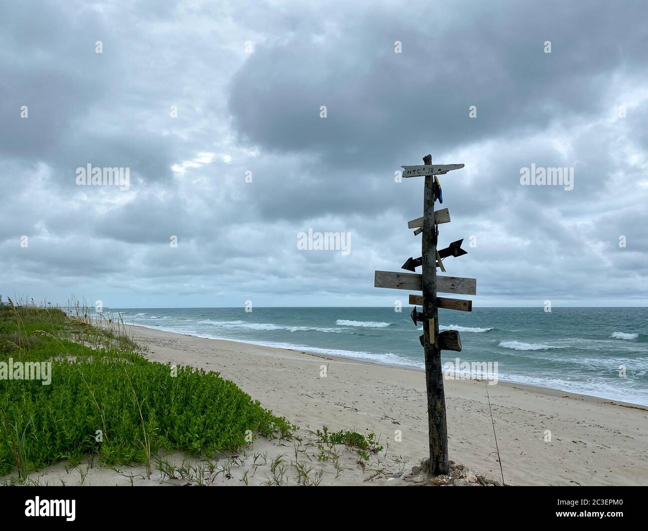 A city directional sign at a beach showing how far cities are from this ...