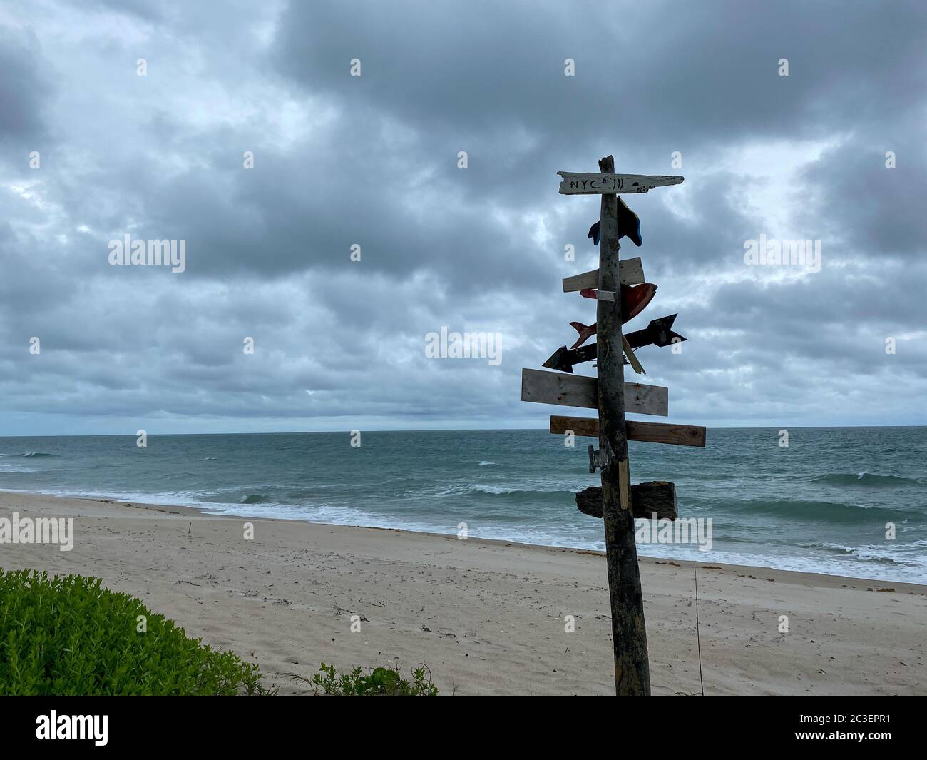 A city directional sign at a beach showing how far cities are from this ...