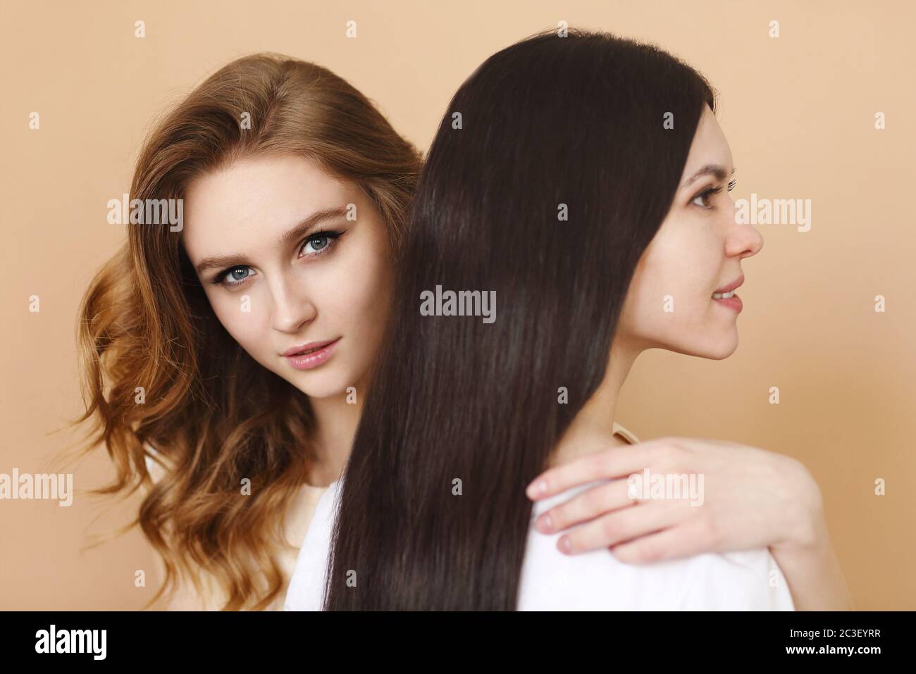 Two beautiful multicultural young women over beige background Stock ...
