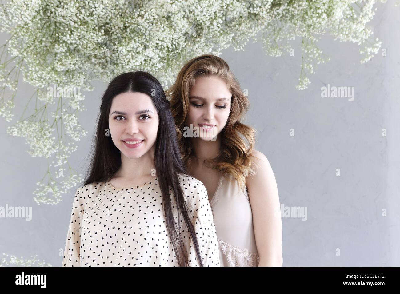 Two beautiful multicultural young women over grey background Stock ...