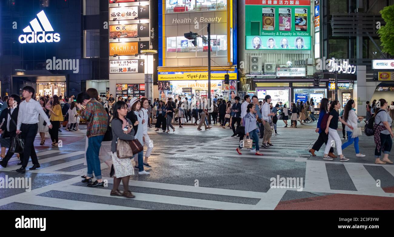 Mass crowd walking across the famous Shibuya pedestrian scramble ...