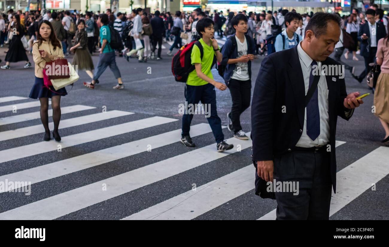 Mass crowd walking across the famous Shibuya pedestrian scramble ...