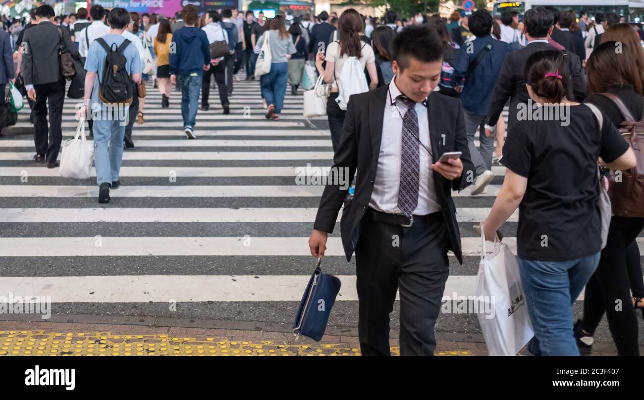 Mass crowd walking across the famous Shibuya pedestrian scramble ...