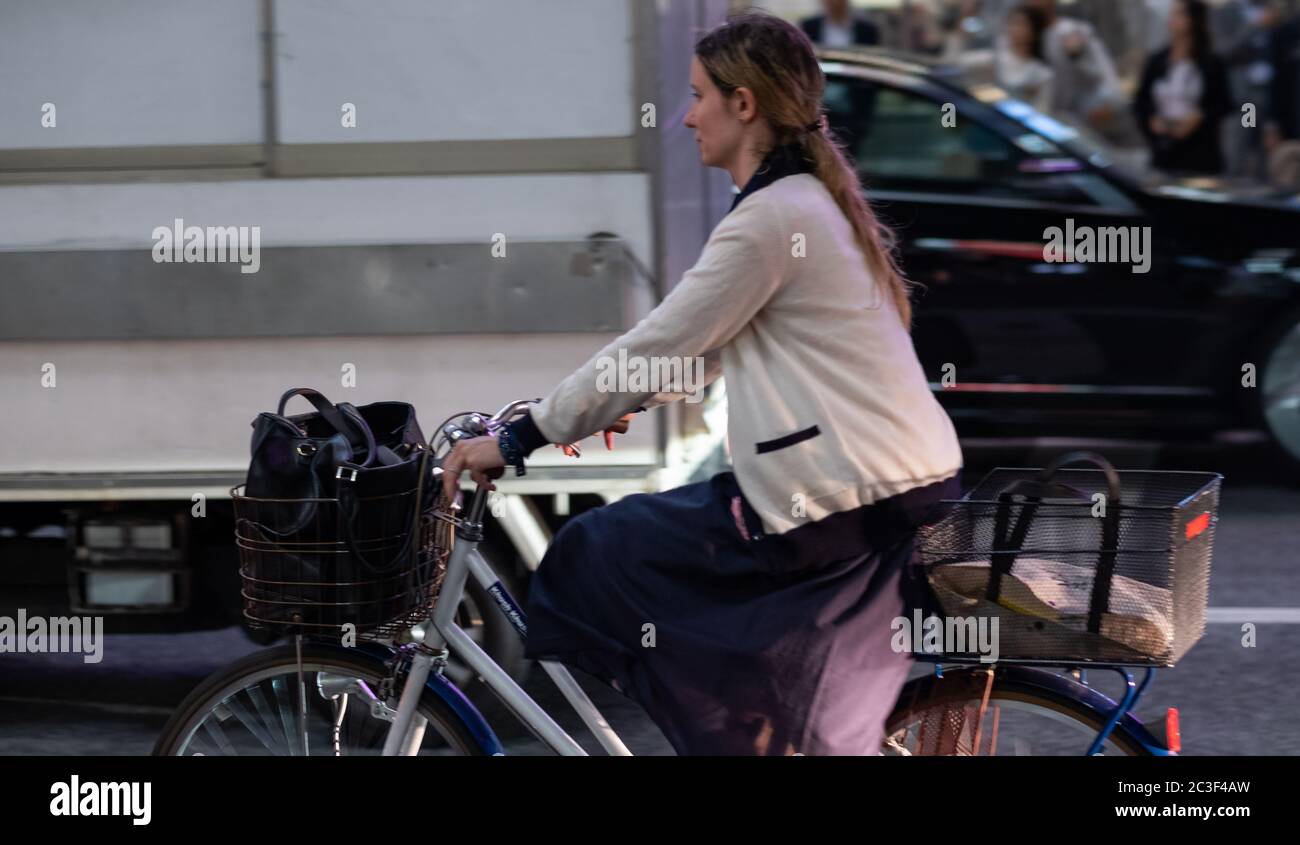 Female commuter cycling in the street of Shibuya, Tokyo, Japan Stock ...