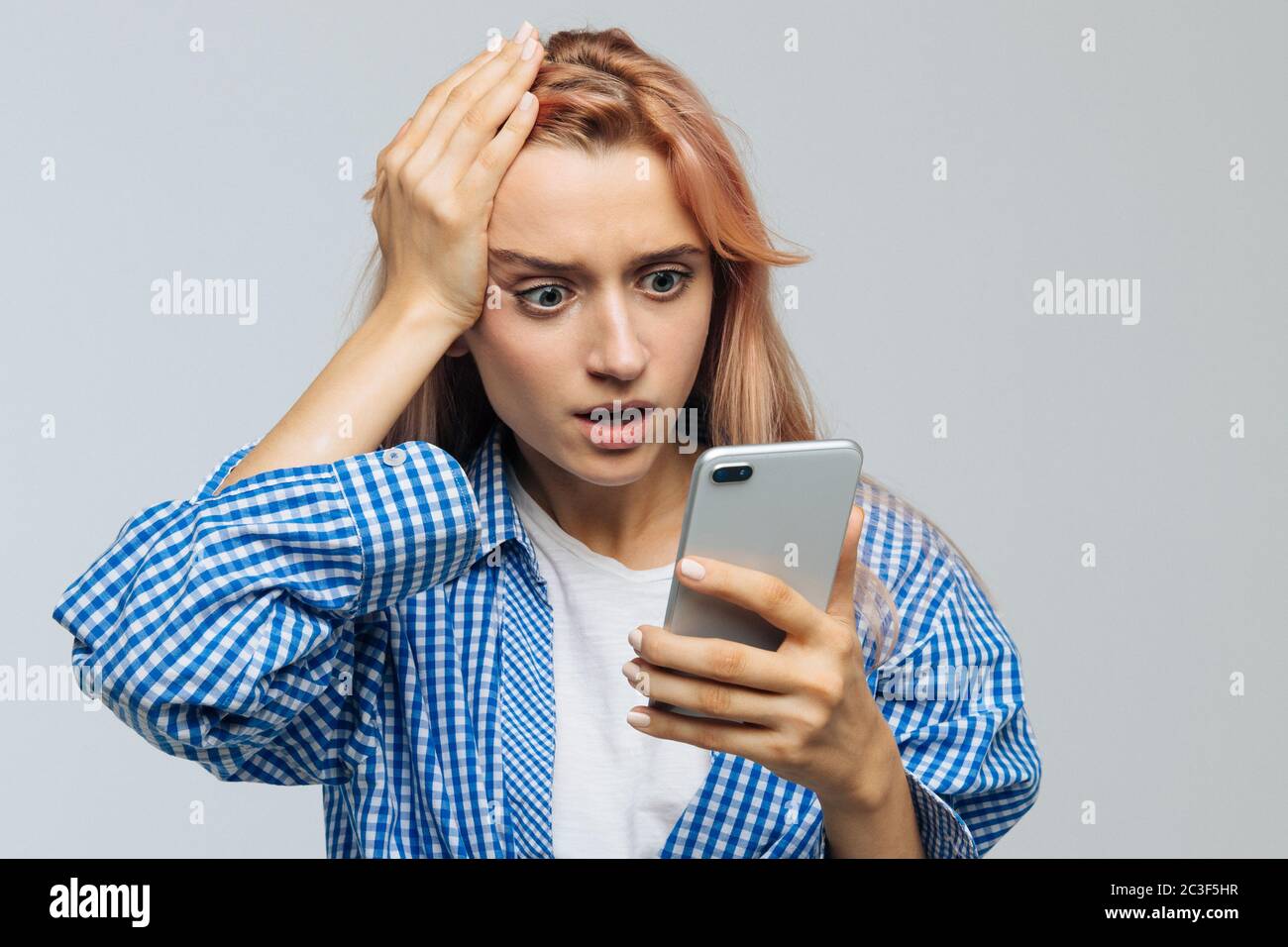 Studio portrait of young cute woman in checked shirt with facepalm ...
