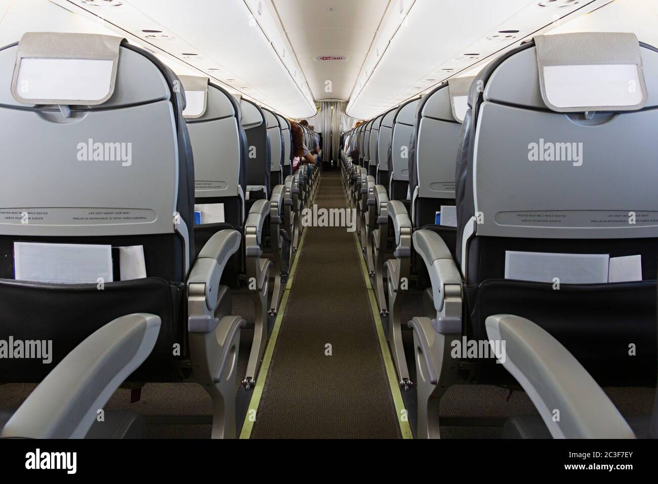 Long aisle with rows of seats and passengers in an airplane cabin ...