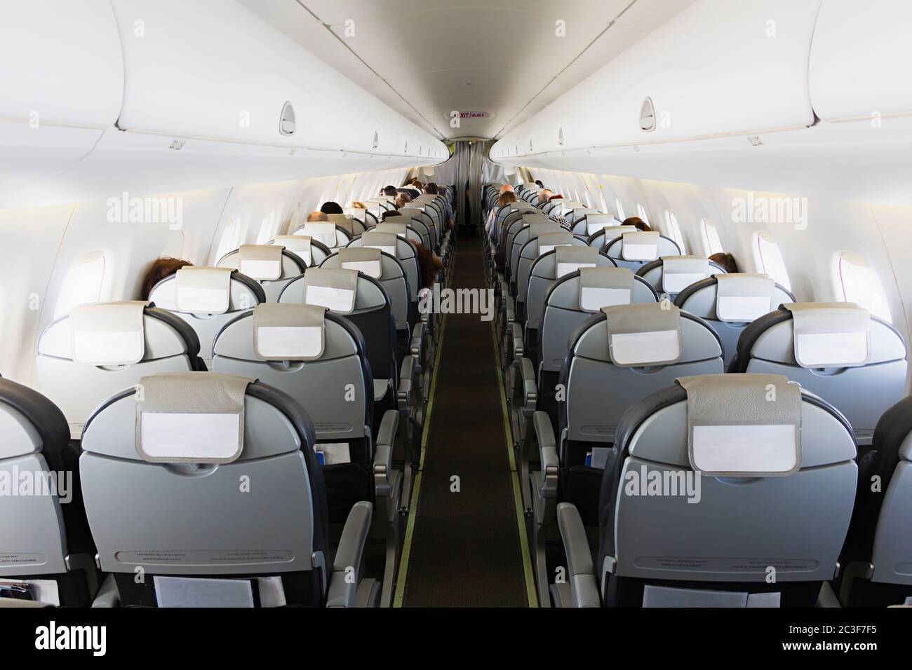 Long aisle with rows of seats and passengers in an airplane cabin ...