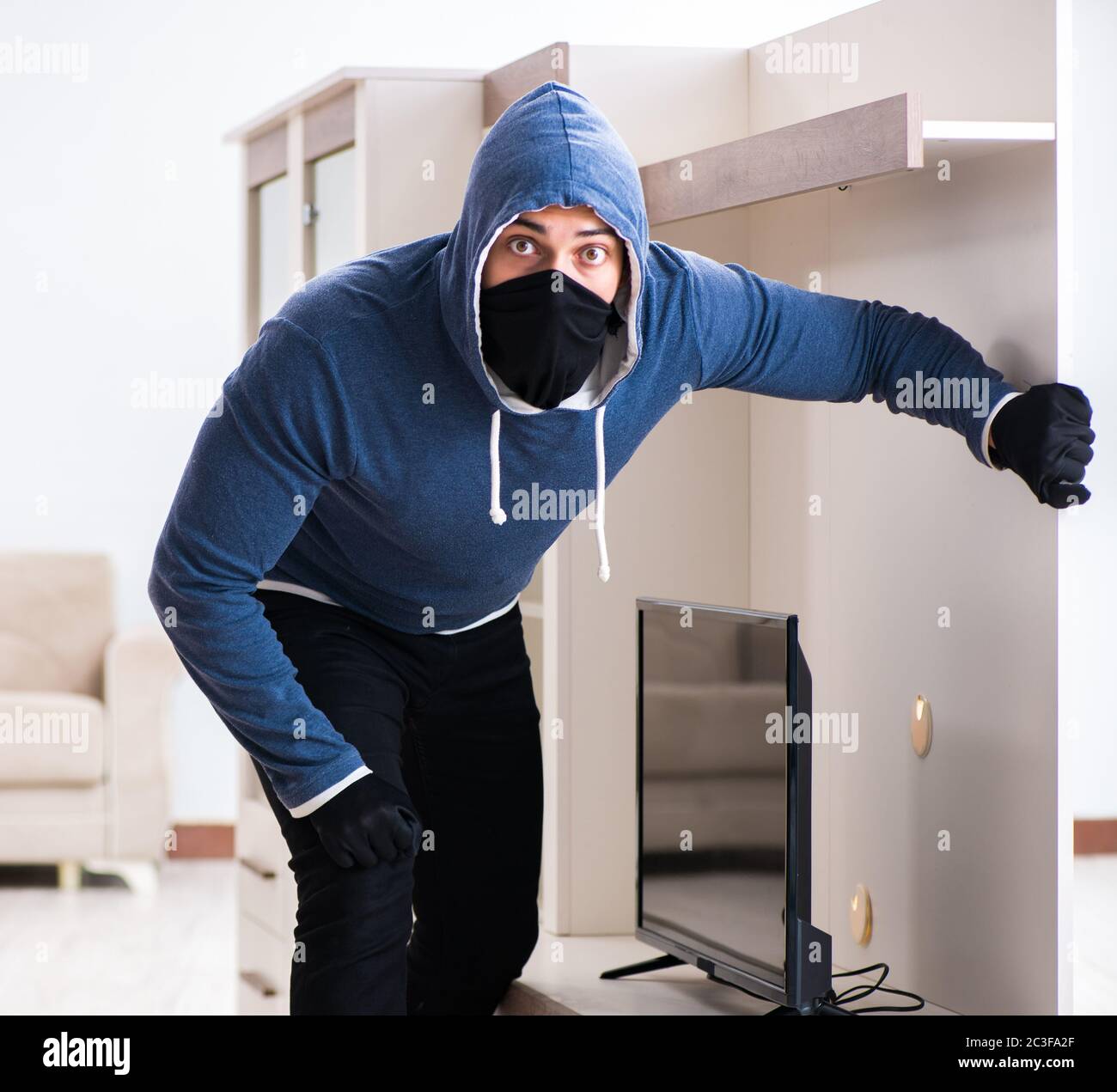 Man burglar stealing tv set from house Stock Photo - Alamy