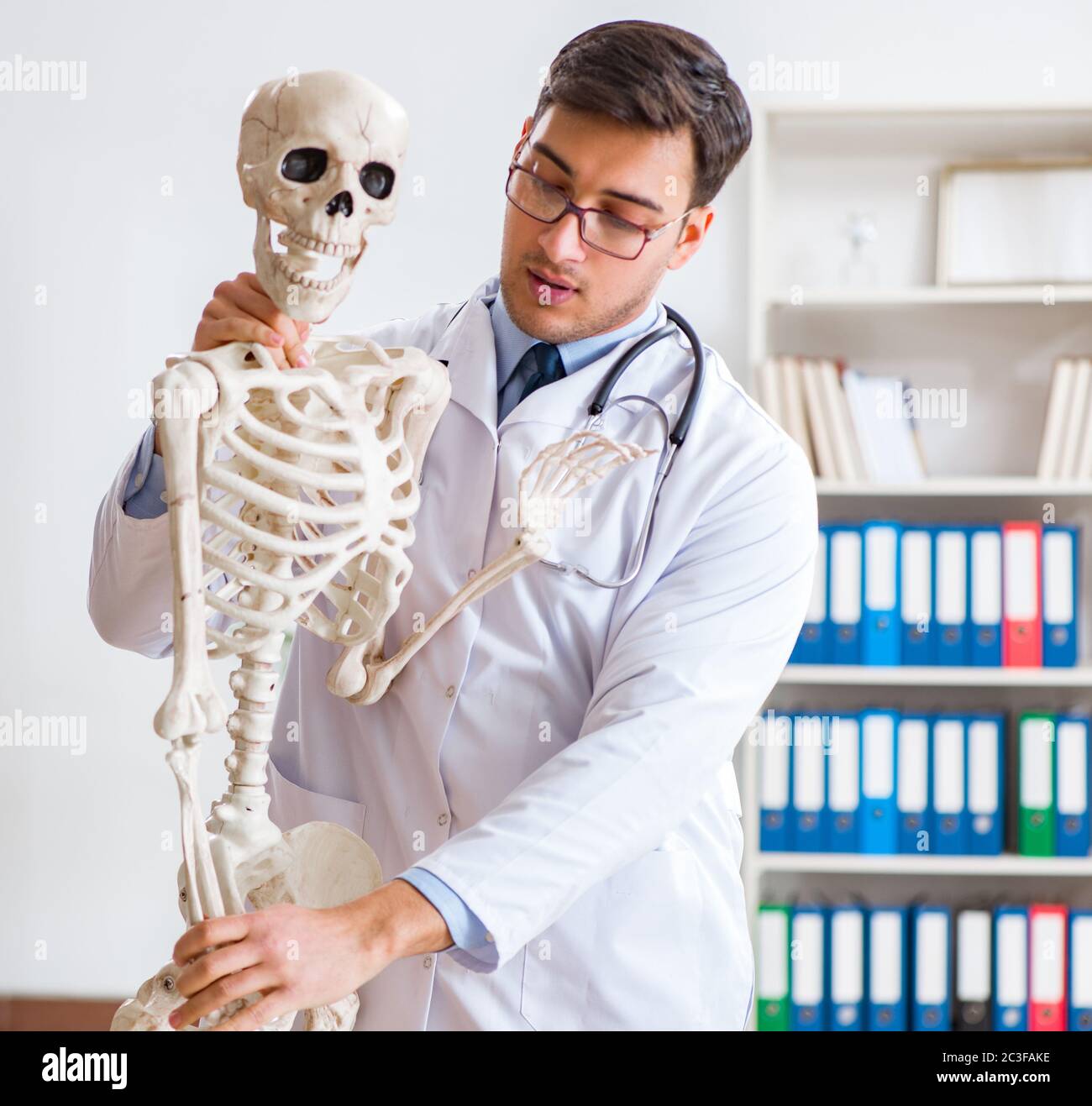 Yong male doctor with skeleton isolated on white Stock Photo - Alamy