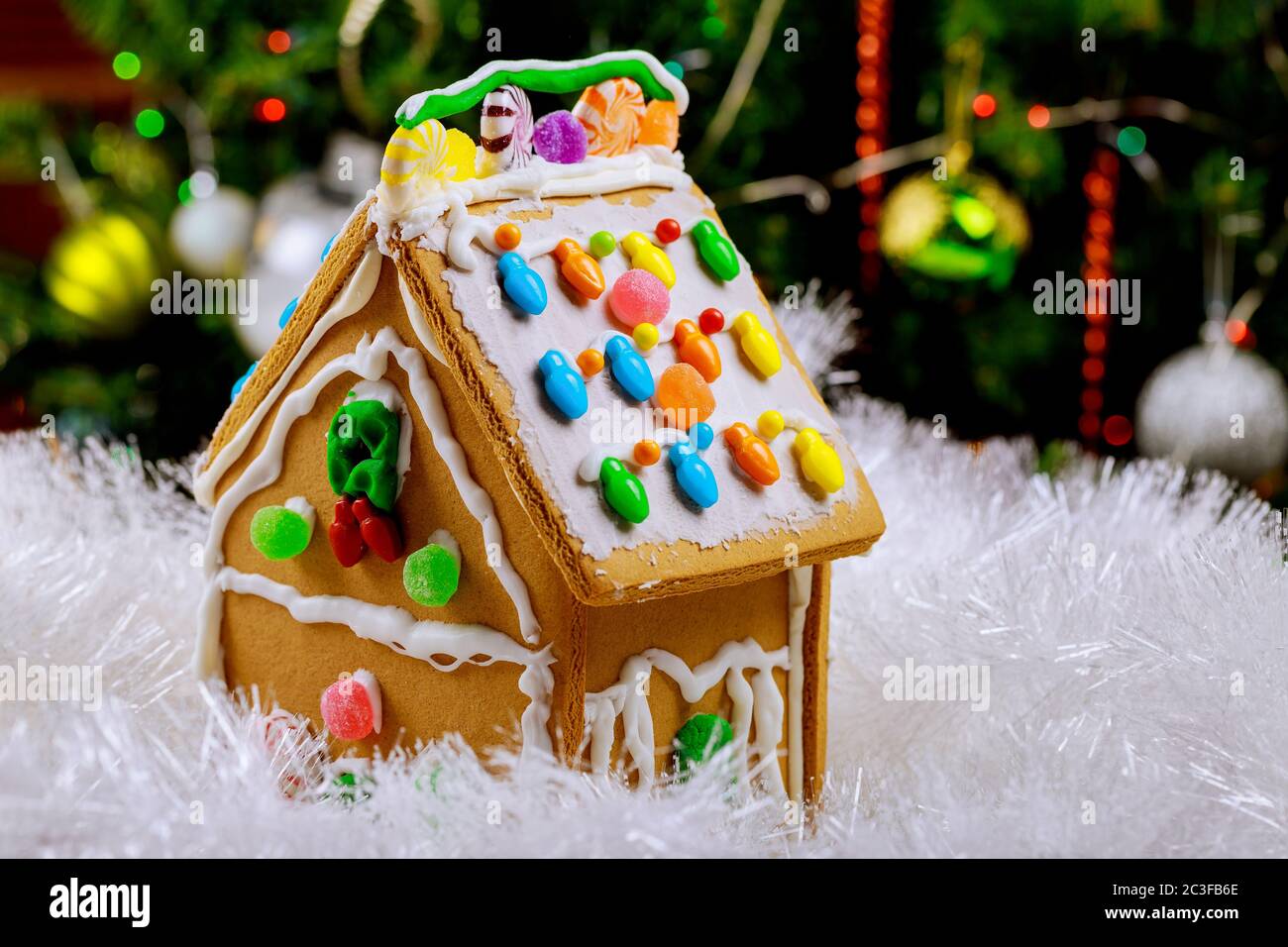 Homemade gingerbread house in snow on decorated christmas tree ...