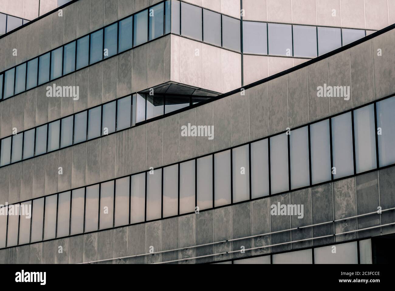 gray high concrete building with reflection of the sky and clouds in ...