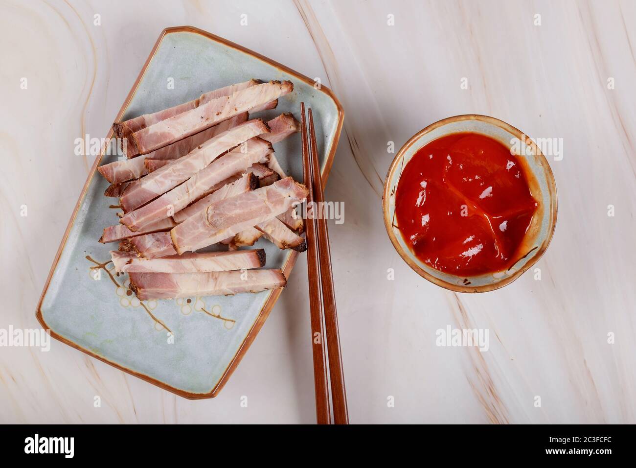 Asian sliced fried meat on a plate with hot sauce and chopstick Stock ...
