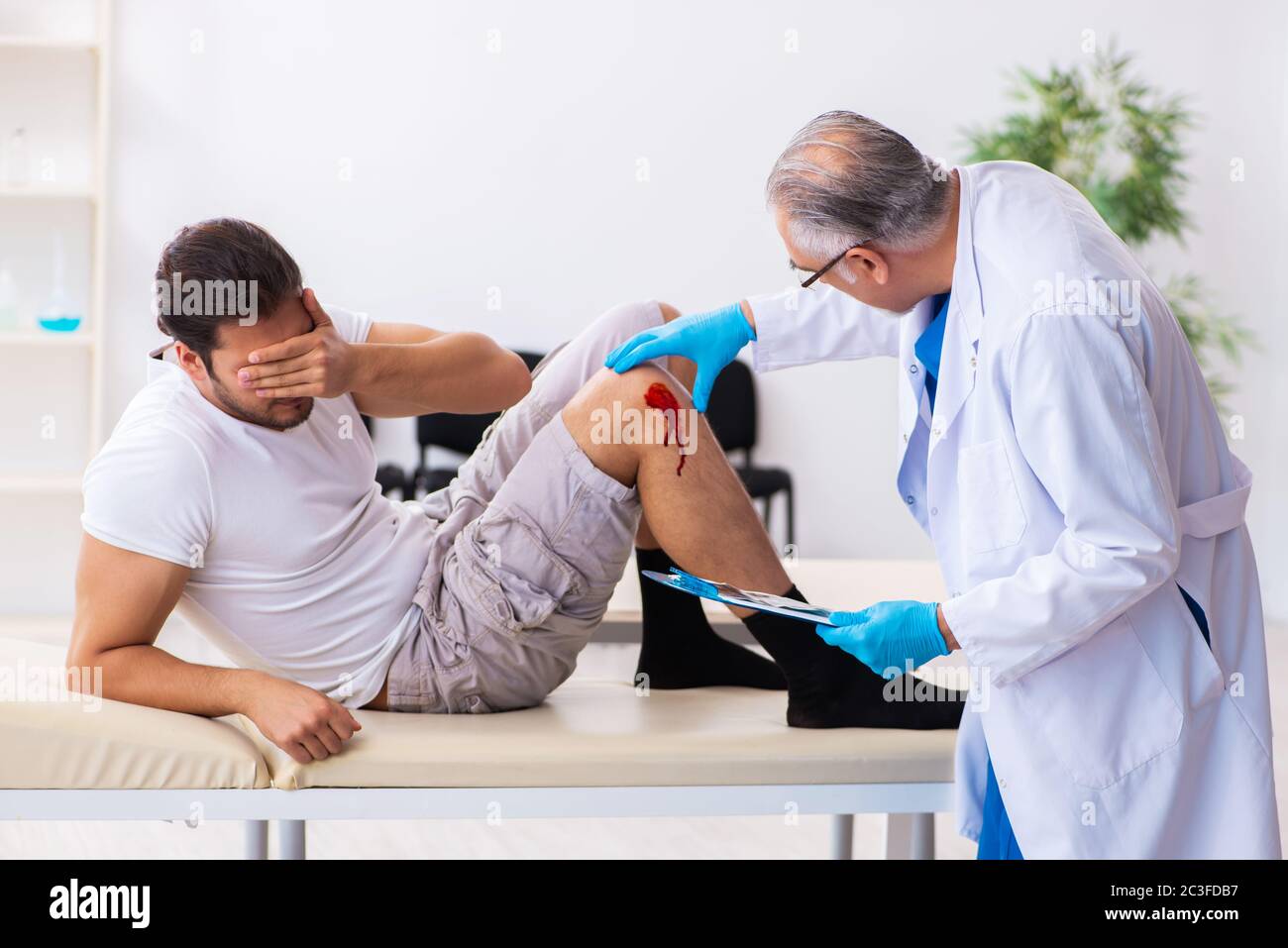 Leg injured man visiting old doctor in first aid concept Stock Photo ...