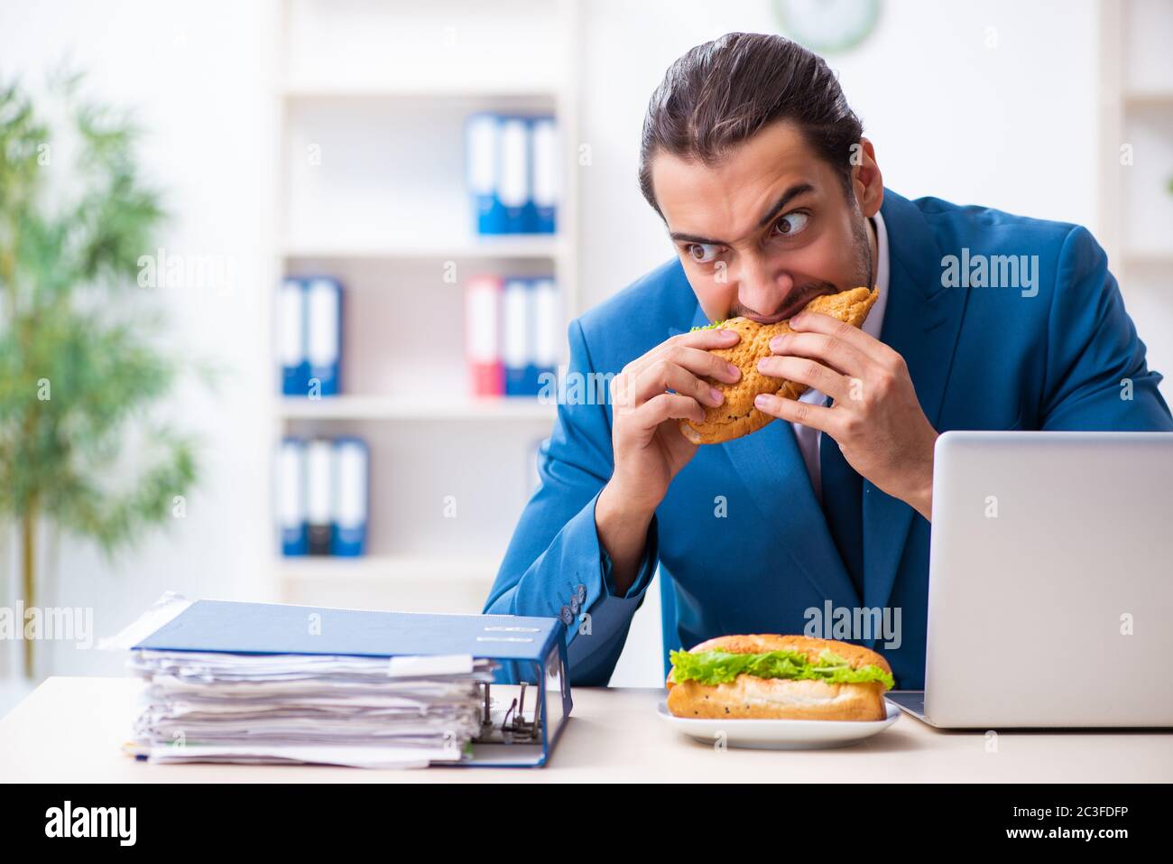 Young male employee having breakfast at workplace Stock Photo - Alamy