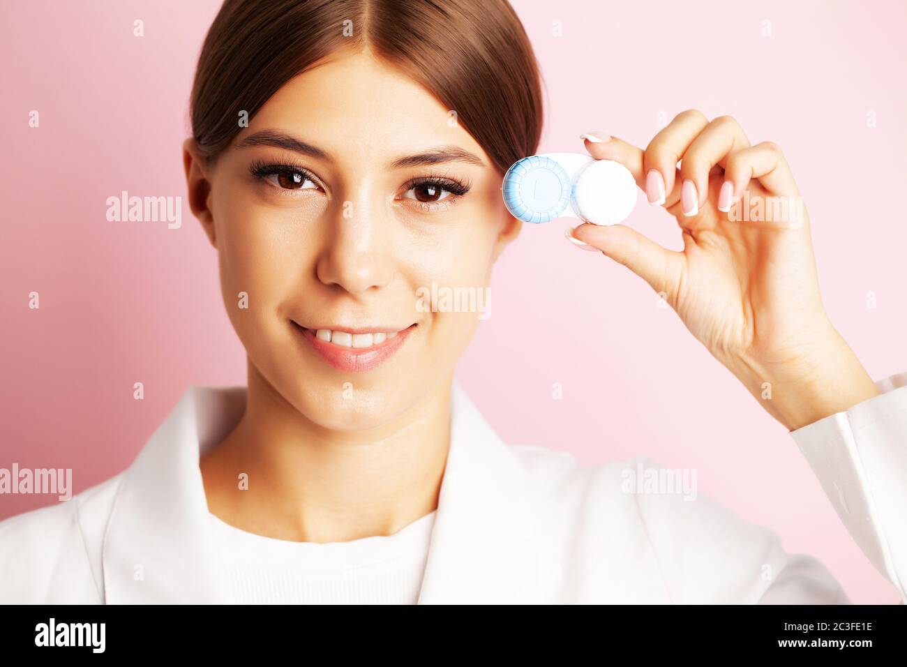 The ophthalmologist holds a container with contact lenses near the eyes ...