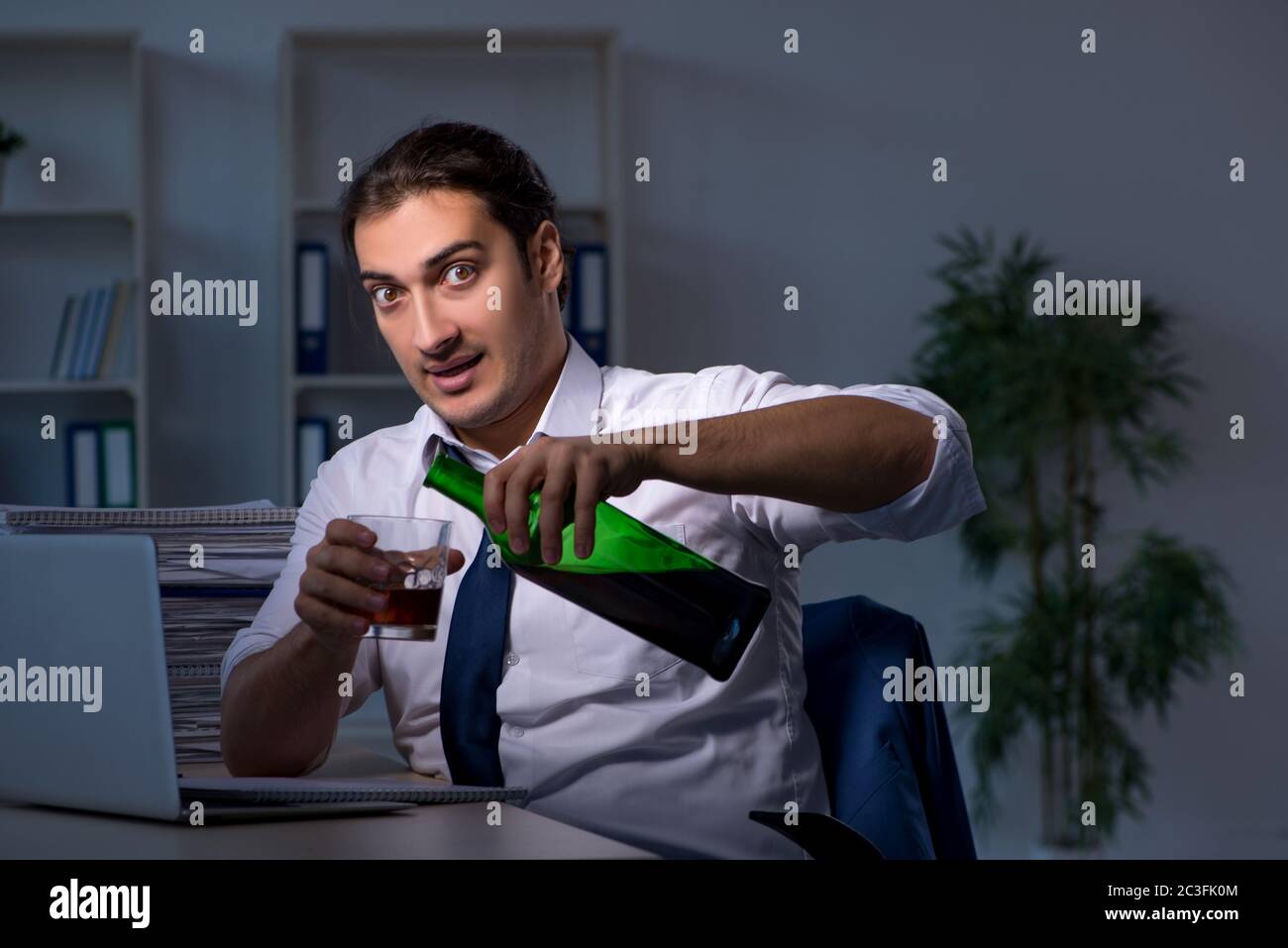 Alcohol addicted businessman working late in the office Stock Photo - Alamy