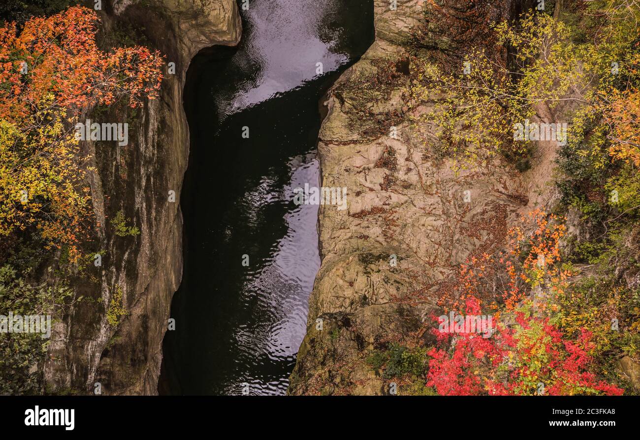 Aerial view of a dark river in a solid rock ravine which is lined with ...