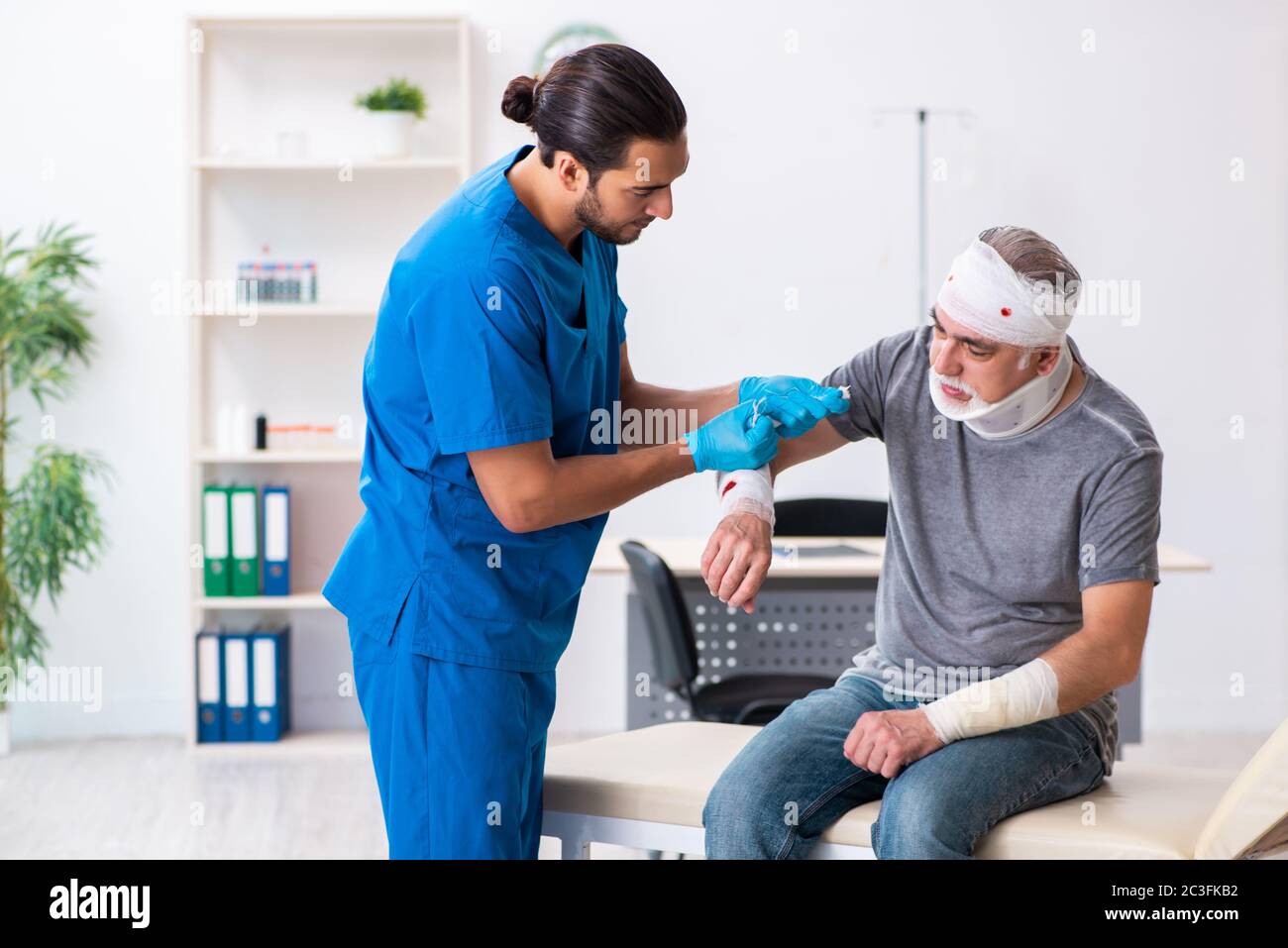 Young male doctor and old patient in first aid concept Stock Photo - Alamy