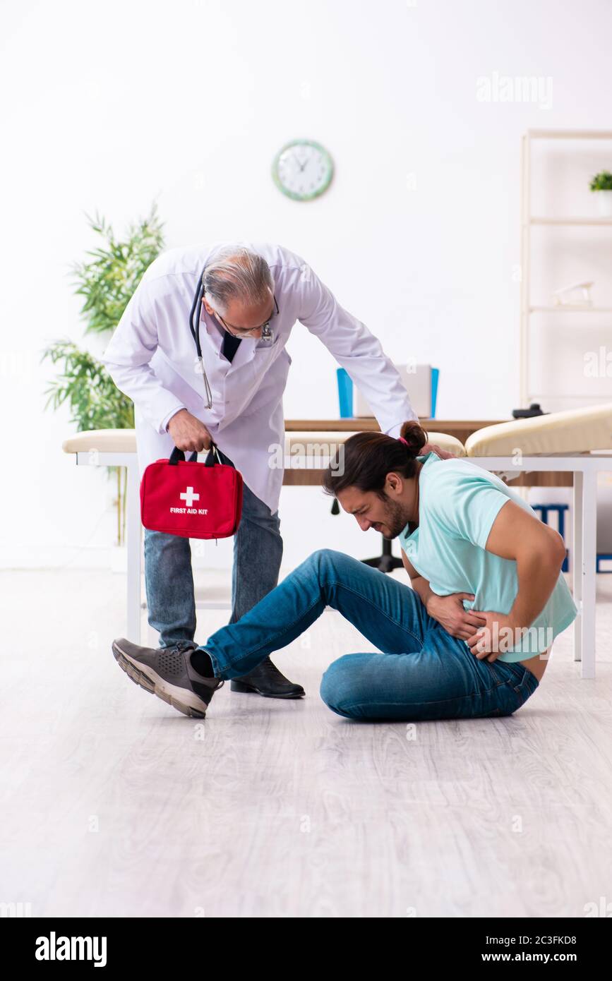 Experienced doctor and young male patient in first aid concept Stock ...
