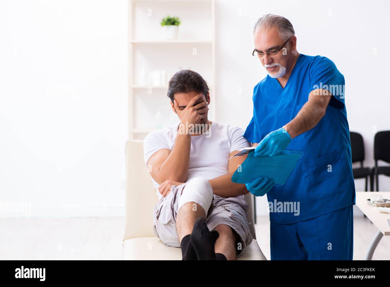 Leg injured man visiting old doctor in first aid concept Stock Photo ...