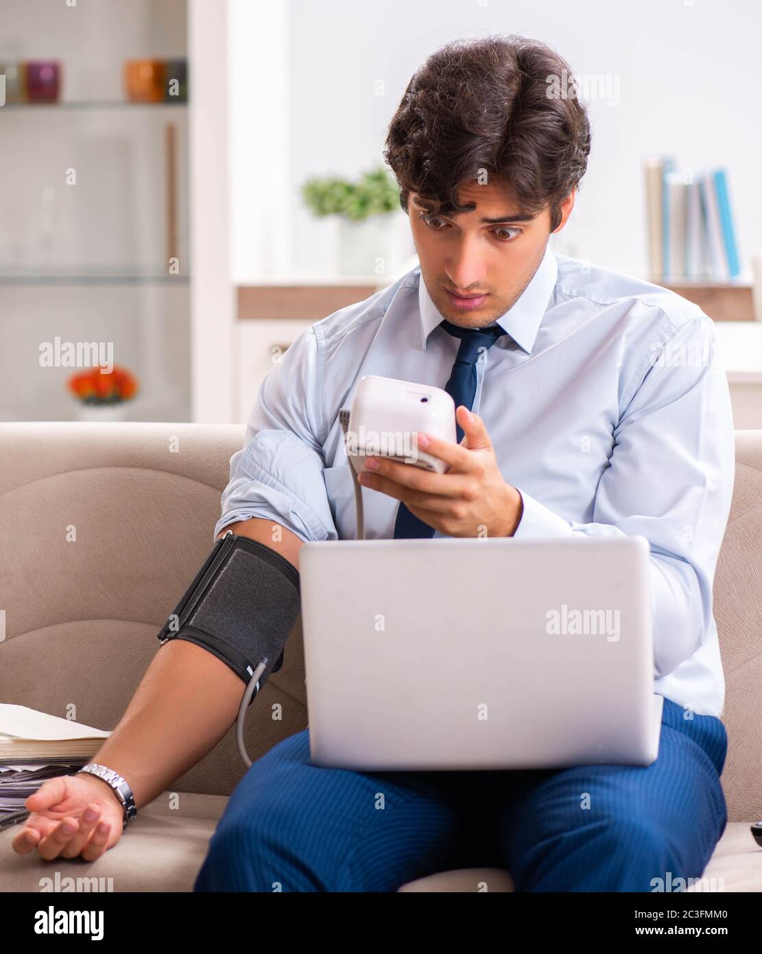 Man under stress measuring his blood pressure Stock Photo - Alamy