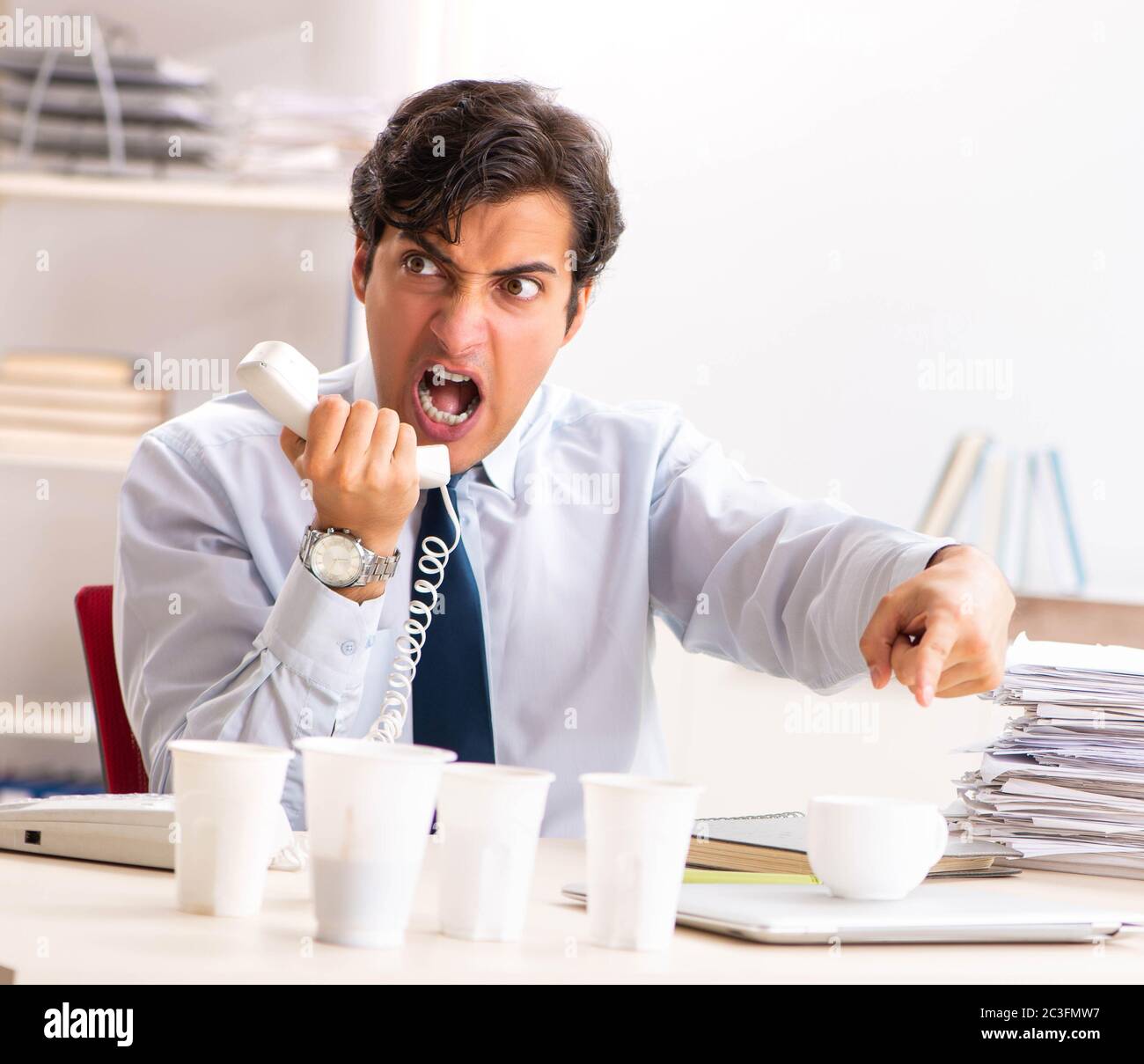 Young employee addicted to coffee Stock Photo - Alamy