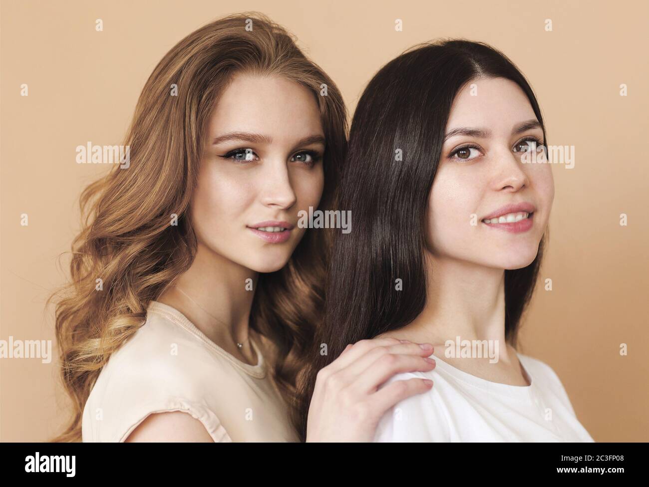 Two beautiful multicultural young women over beige background Stock ...