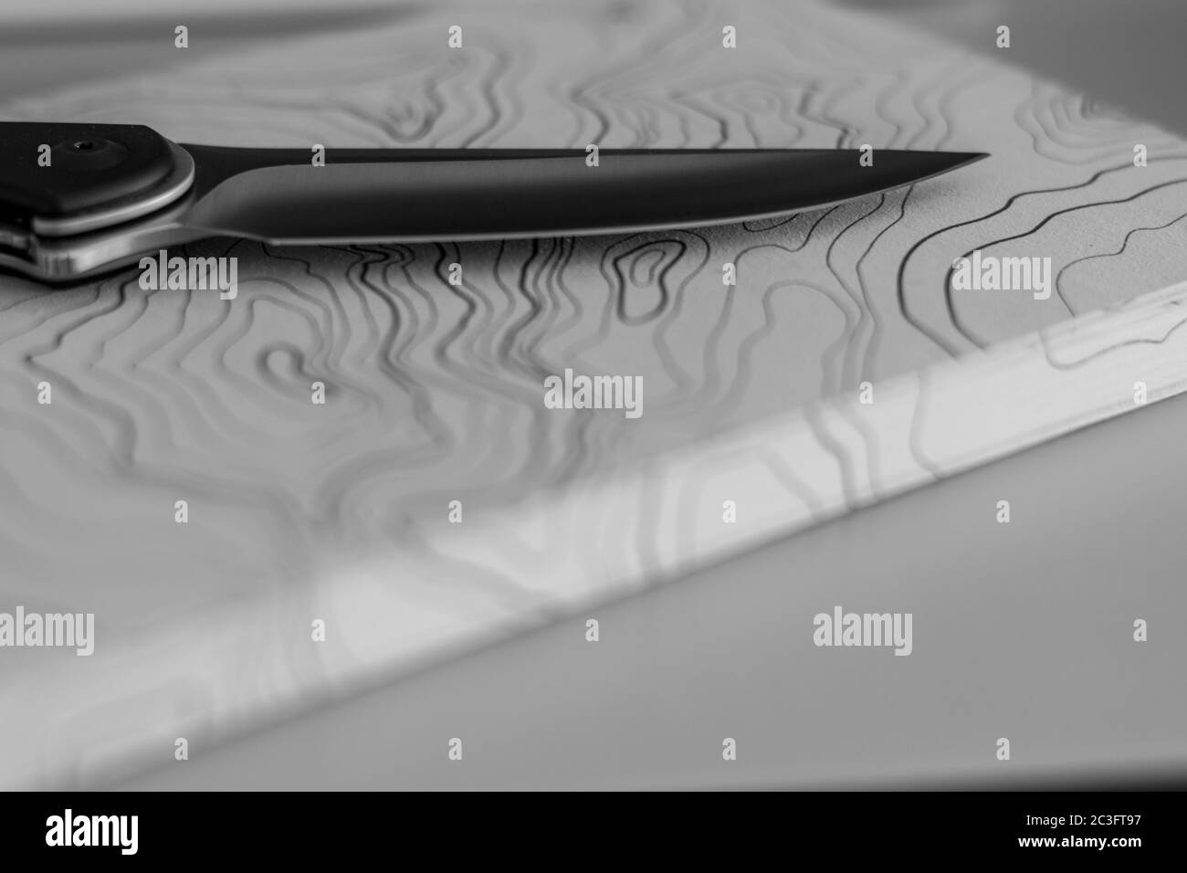Isolated close up of a single blade knife on a topographic map notebook ...