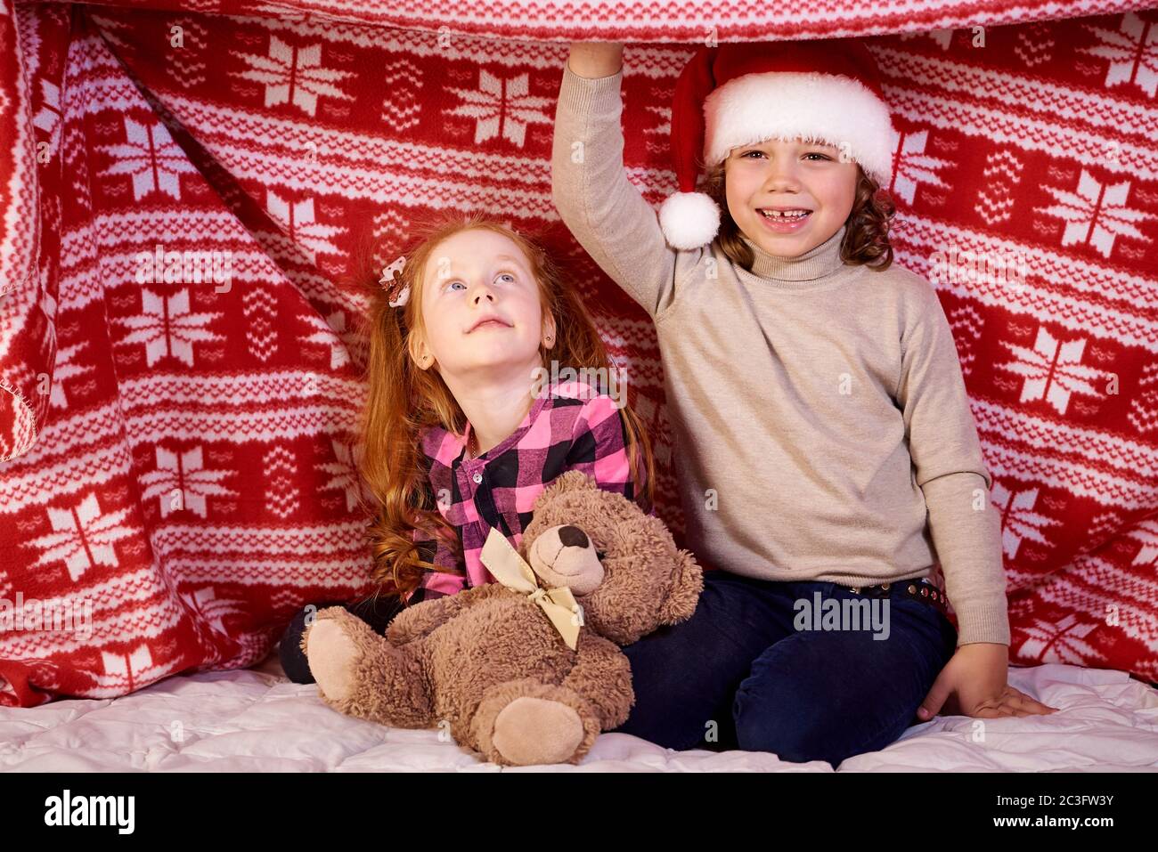 Happy children play on the bed under a red plaid Stock Photo - Alamy