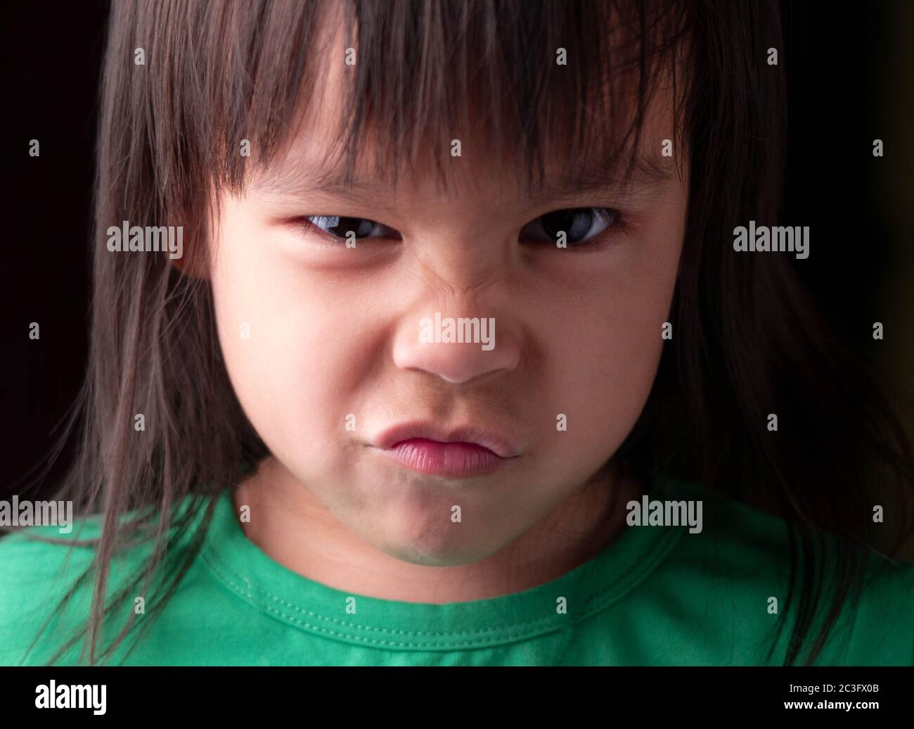 Portrait face of Asian little child girl with angry expression on dark ...