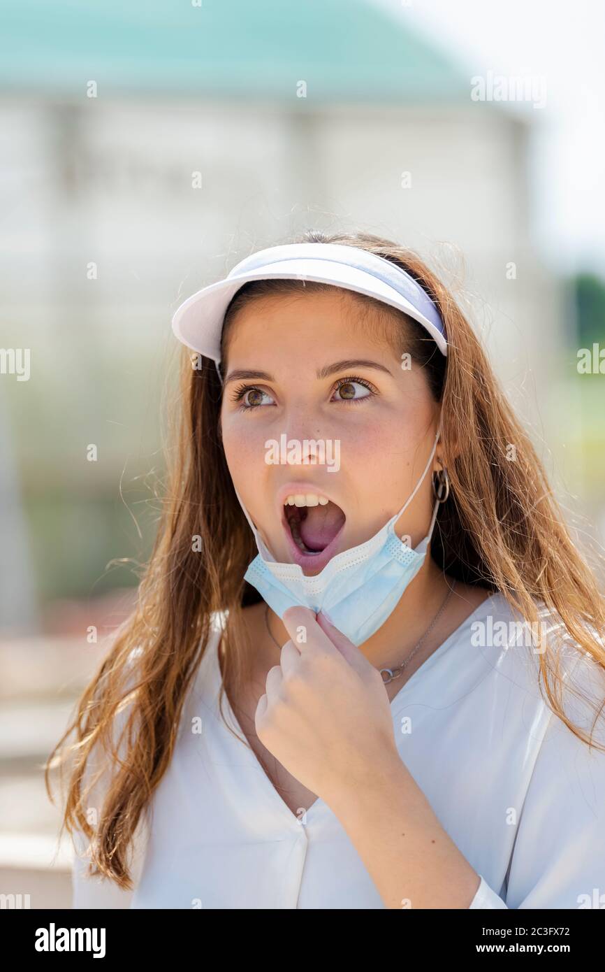 Close up of a surprised looking young woman pulling down her surgical ...