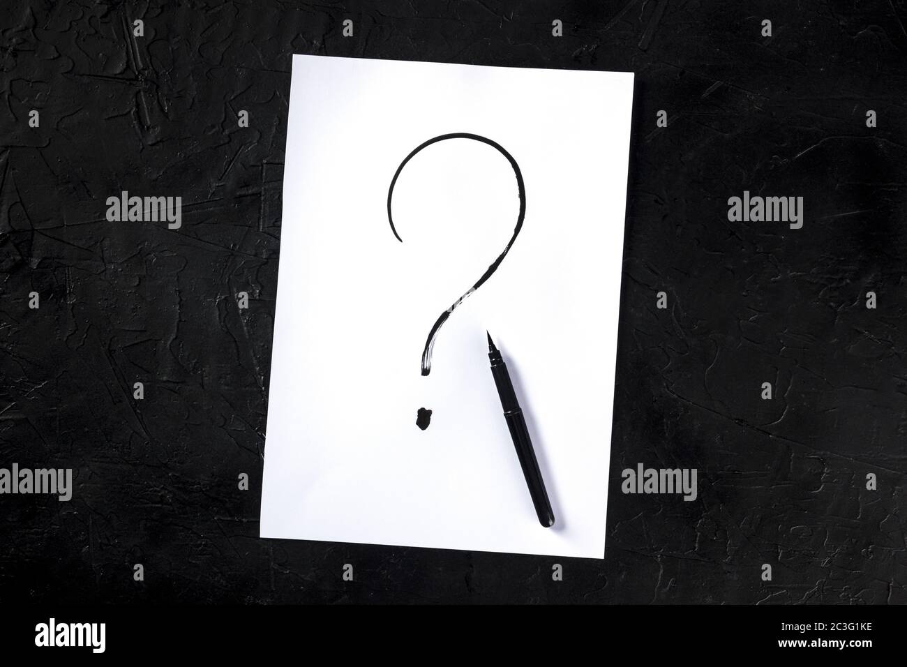 Question mark, written in ink on a piece of standard office paper, shot ...